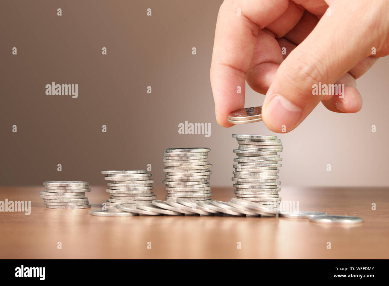 Hand putting stack of a coins Stock Photo - Alamy