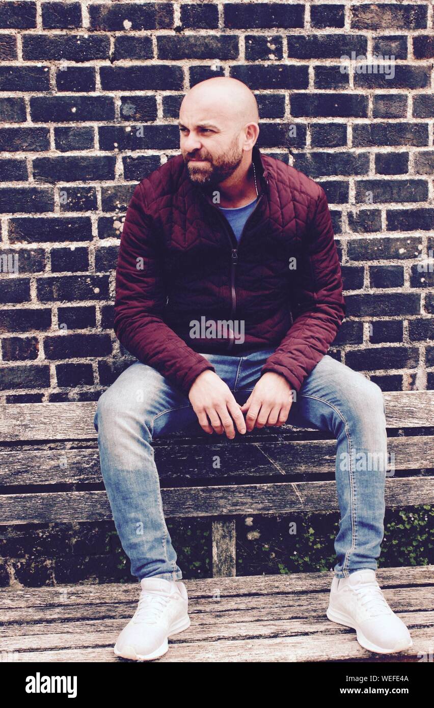 Man sitting on brick wall hi-res stock photography and images - Alamy