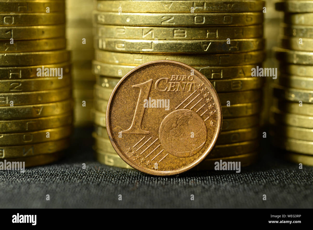 One euro cent coin placed on edge in front of piles of coins Stock ...