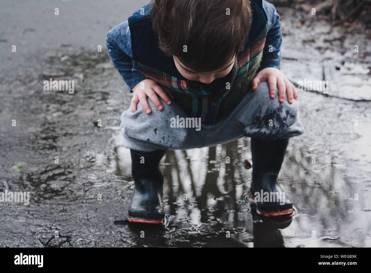 Full Length Of Boy Crouching On Puddle Stock Photo - Alamy