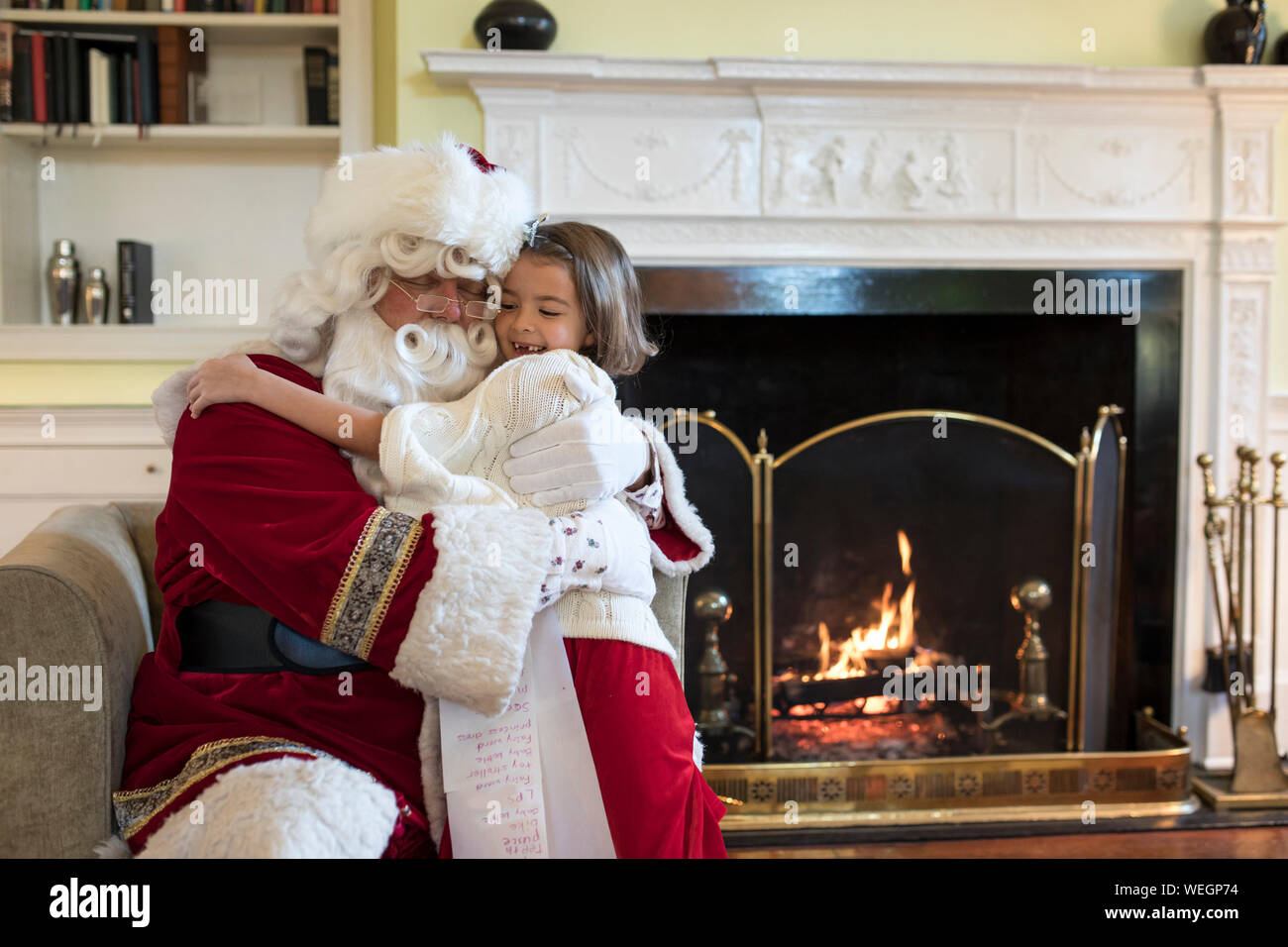 Little girl giving Santa Clause a hug in front of fireplace Stock Photo ...