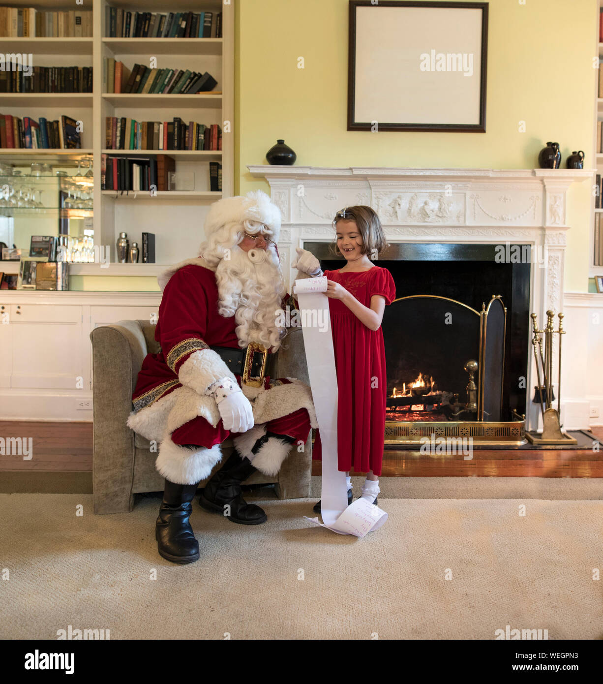 Little girl asking Santa Clause for a gift from a long list Stock Photo ...