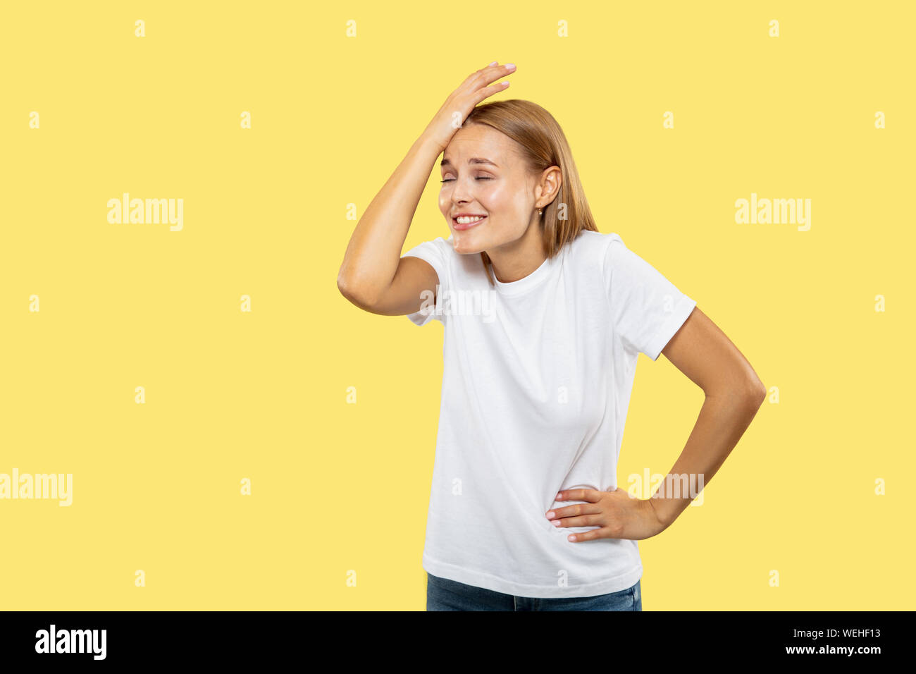 Caucasian young woman's half-length portrait on yellow studio ...