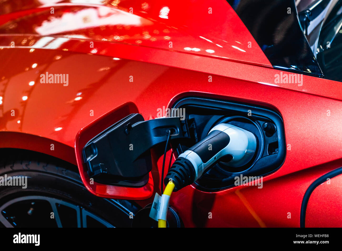 Red EV Car at charging station with the power cable supply plugged in ...