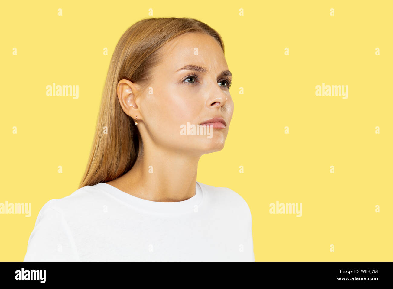 Caucasian young woman's half-length portrait on yellow studio ...