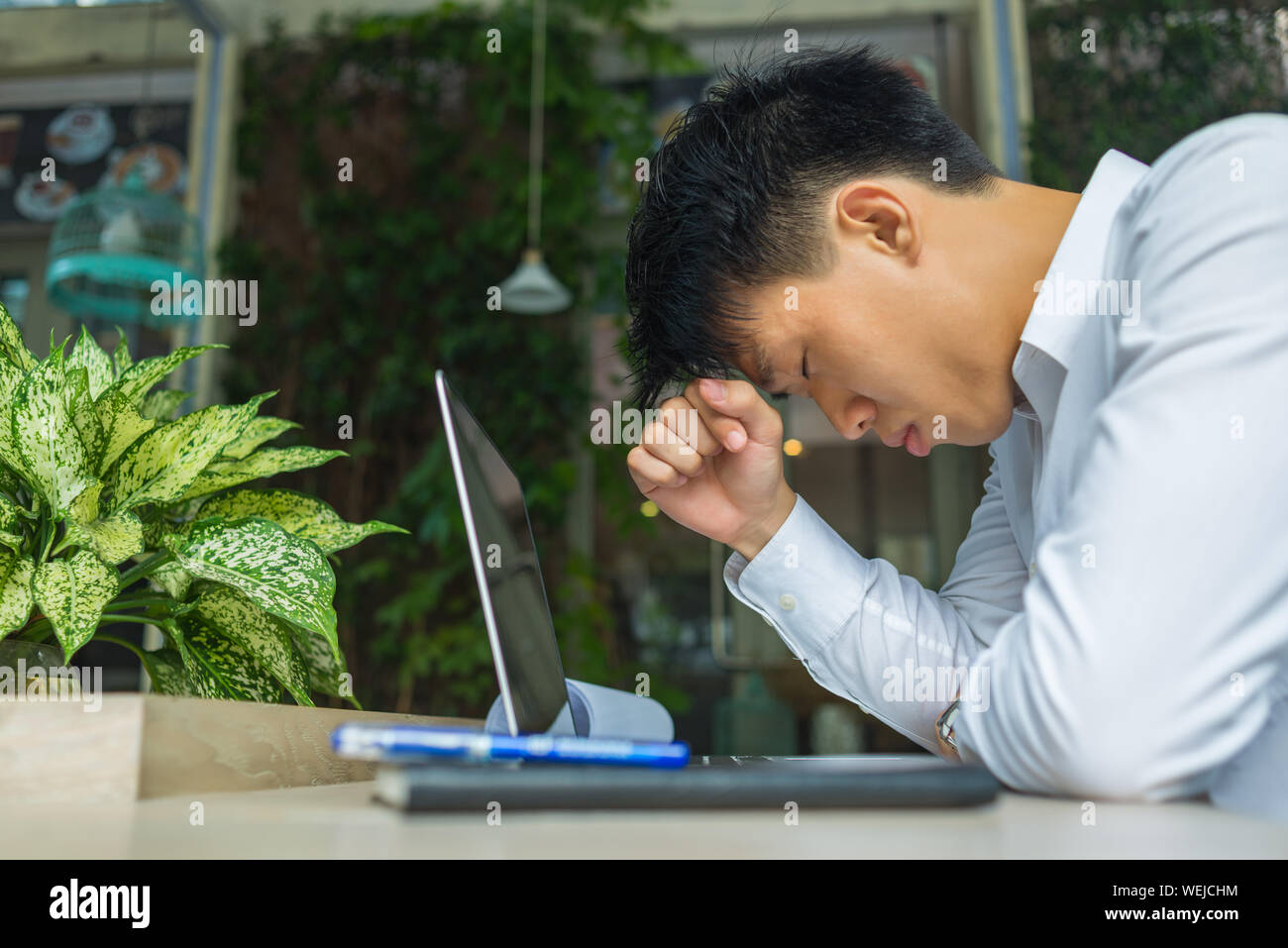 Tired Asian businessman close eye in front of laptop Stock Photo - Alamy