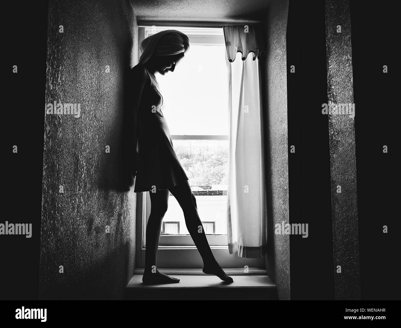 Woman standing by full length window Black and White Stock Photos ...
