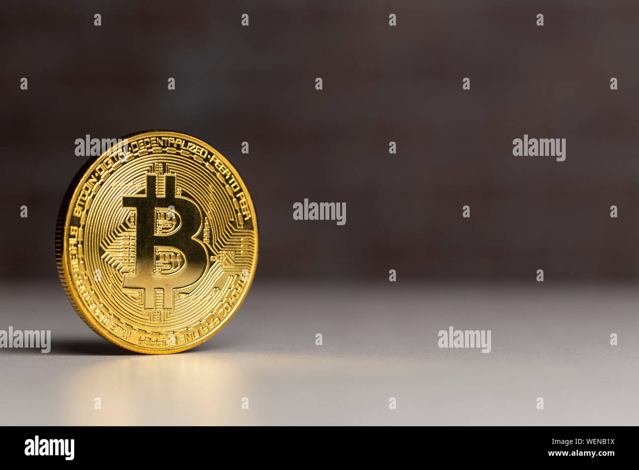 physical bitcoin standing at a white table in front of a brick wall ...
