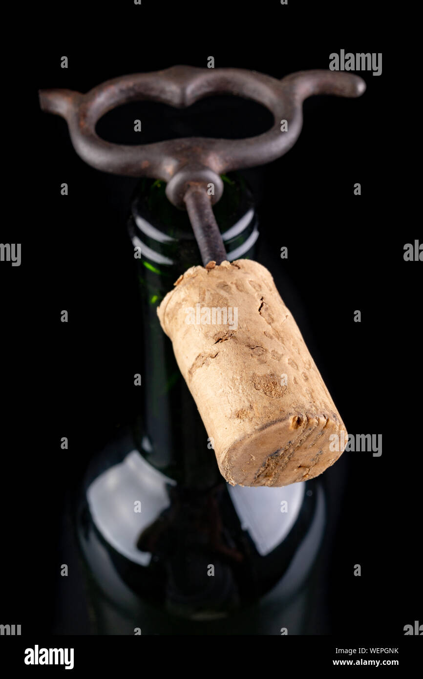 A bottle of wine and a corkscrew on a dark table. Opening good wine ...