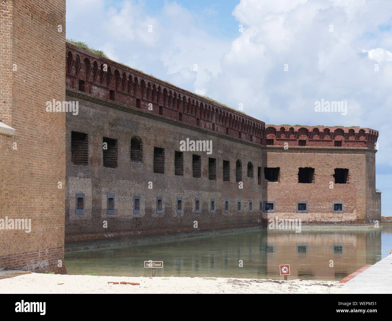 Moat on one side of Fort Jefferson, with warning signs in the banks ...
