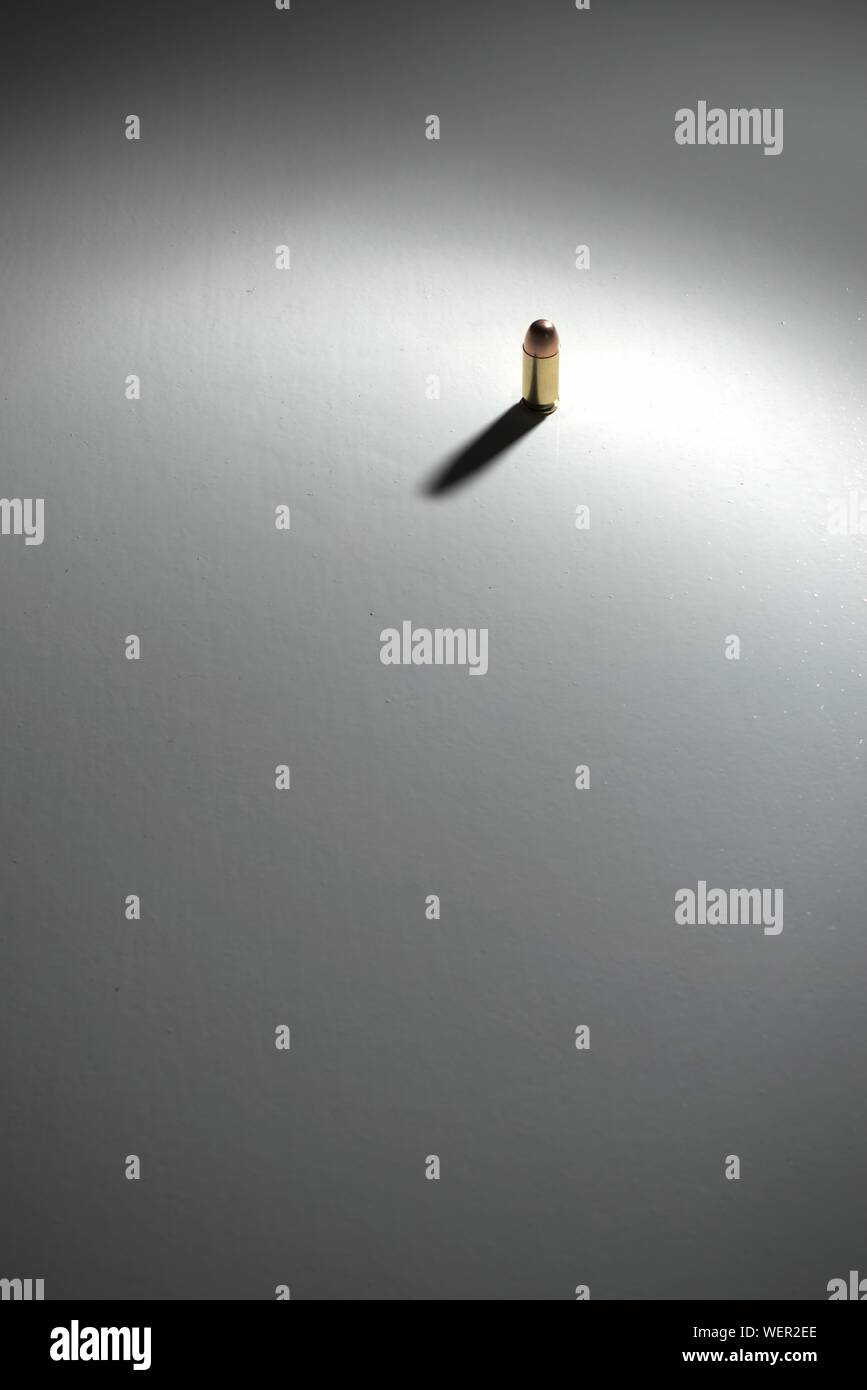 Bullet (.45 FMJ Auto) standing on a white surface with long dramatic ...