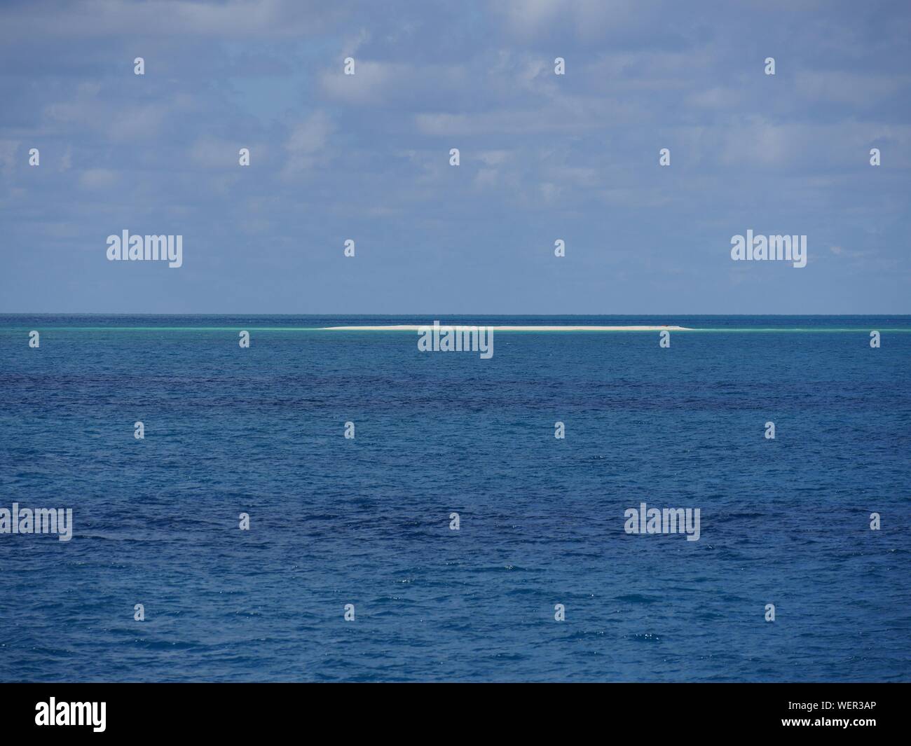 Wide shot of the ocean with a sliver of a white sand bar in the ...