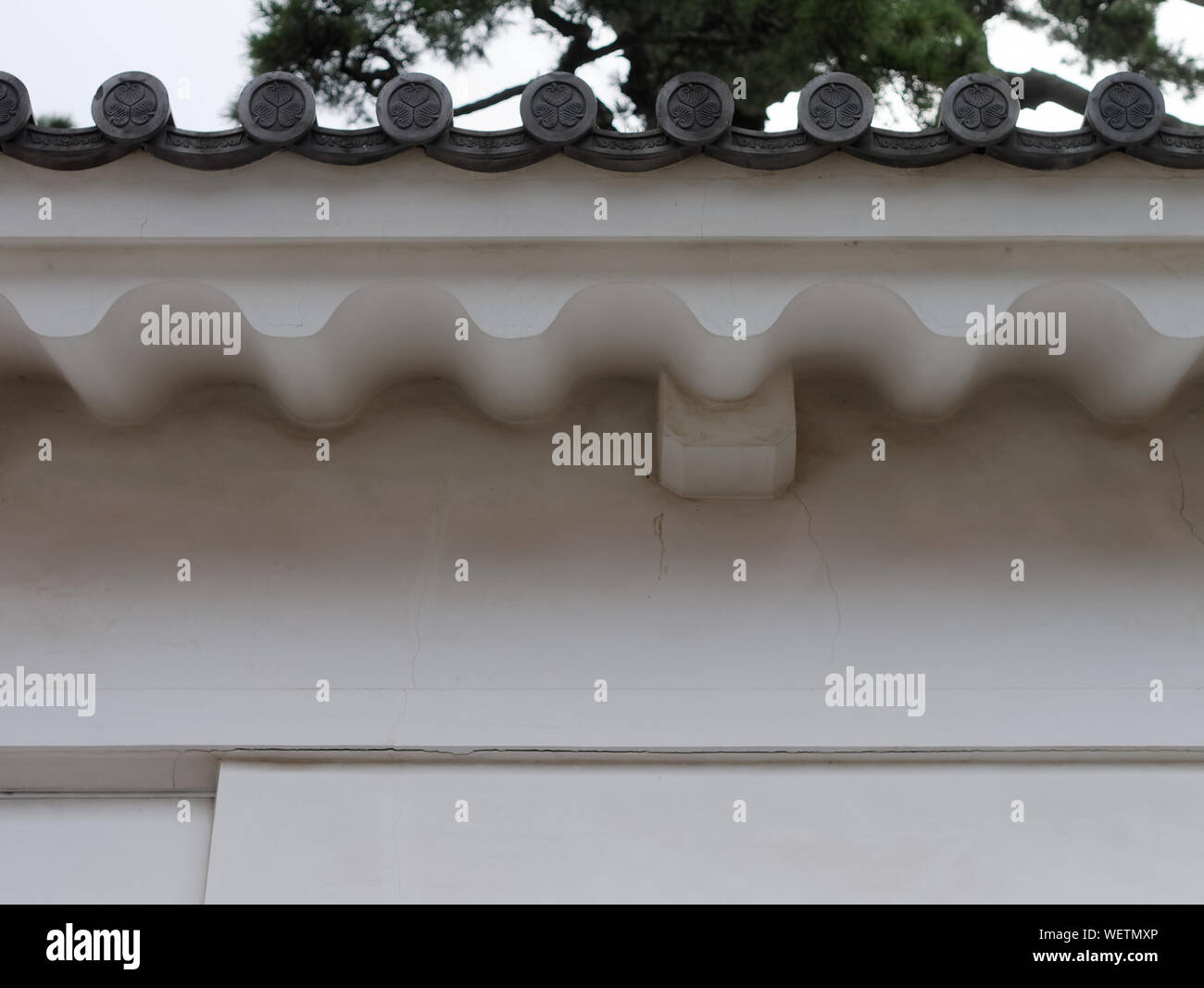 Detail of white wall and ornate roof tiles of a traditional Japanese ...