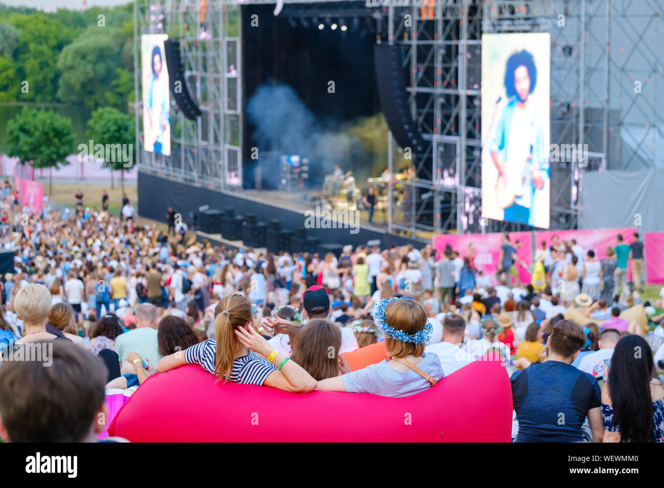 Friends watching concert at open air music festival, back view, stage ...