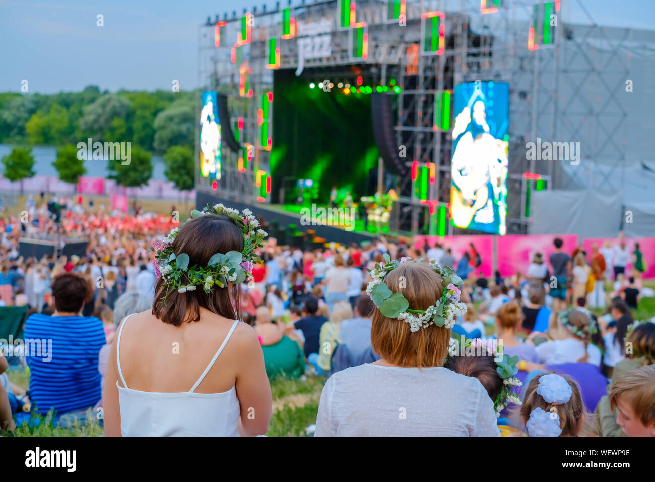 Friends watching concert at open air music festival, back view, stage ...
