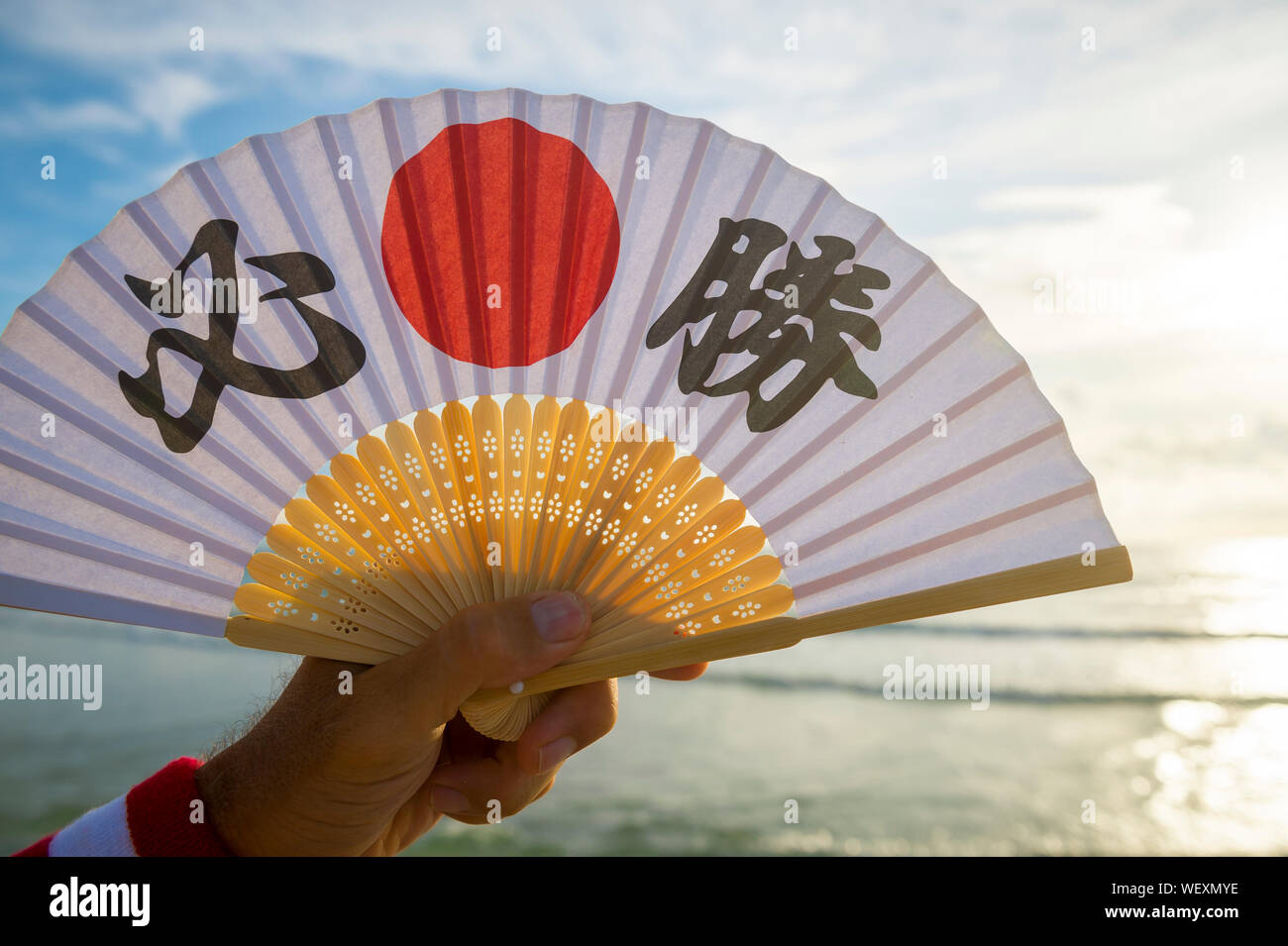 Hand of Japanese sports supporter holding a fan decorated with kanji ...