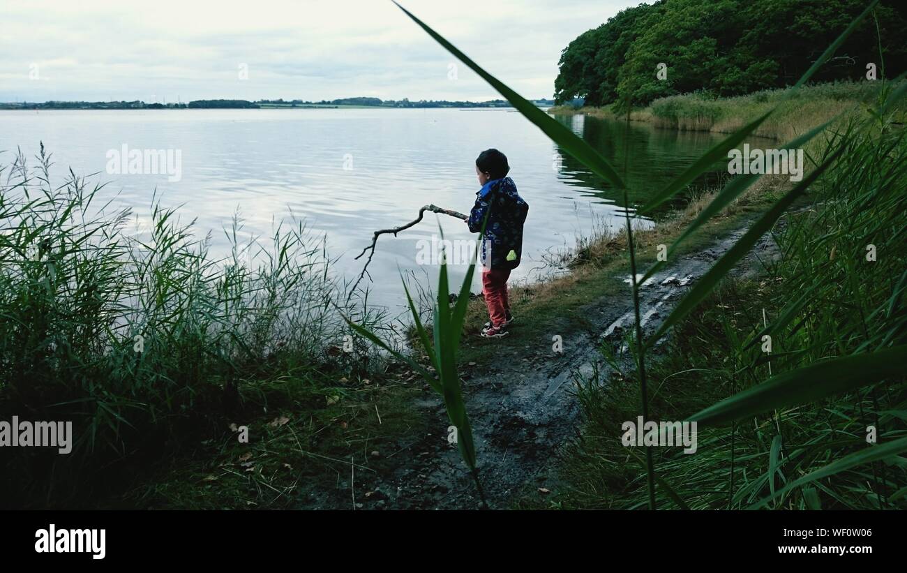 Full Length Of Boy Playing With Stick At Lakeshore Stock Photo - Alamy