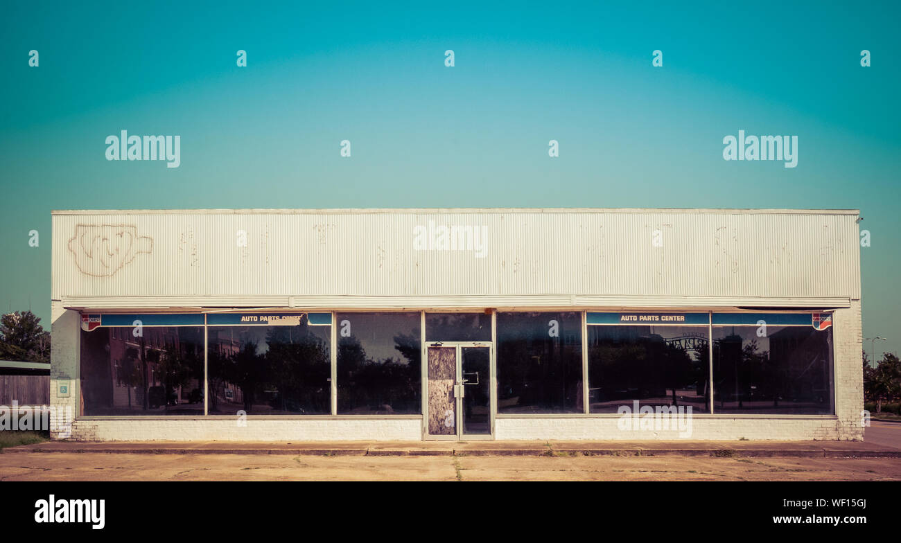 Abandoned old white commercial building in distress, once an Auto Parts ...