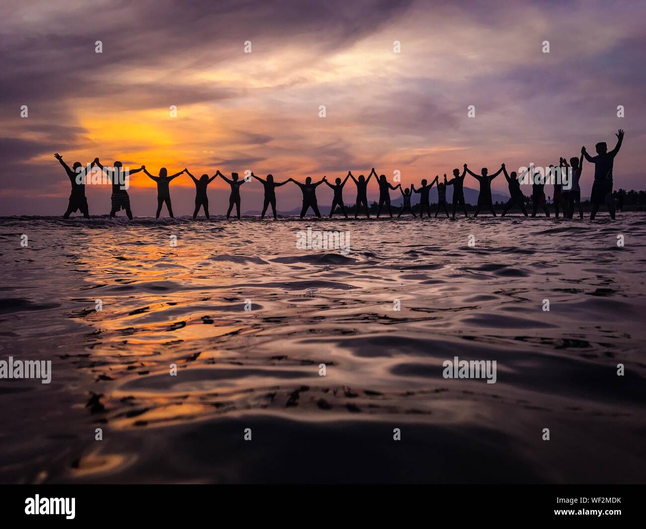 Group Holding Hands Sunset