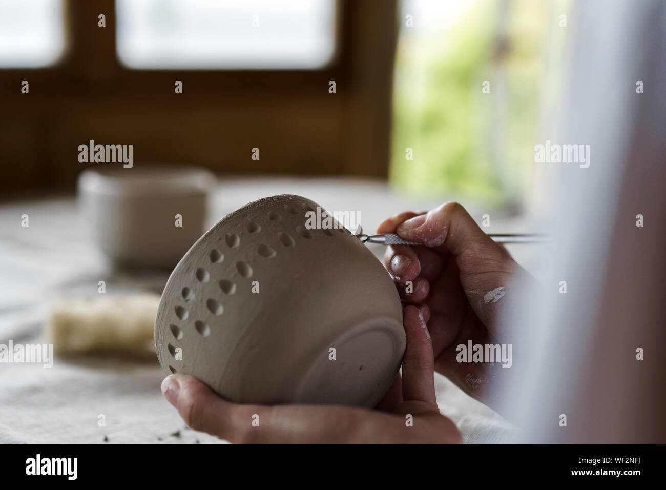Female hands handle the edge of a wet clay bowl with a stick Stock ...