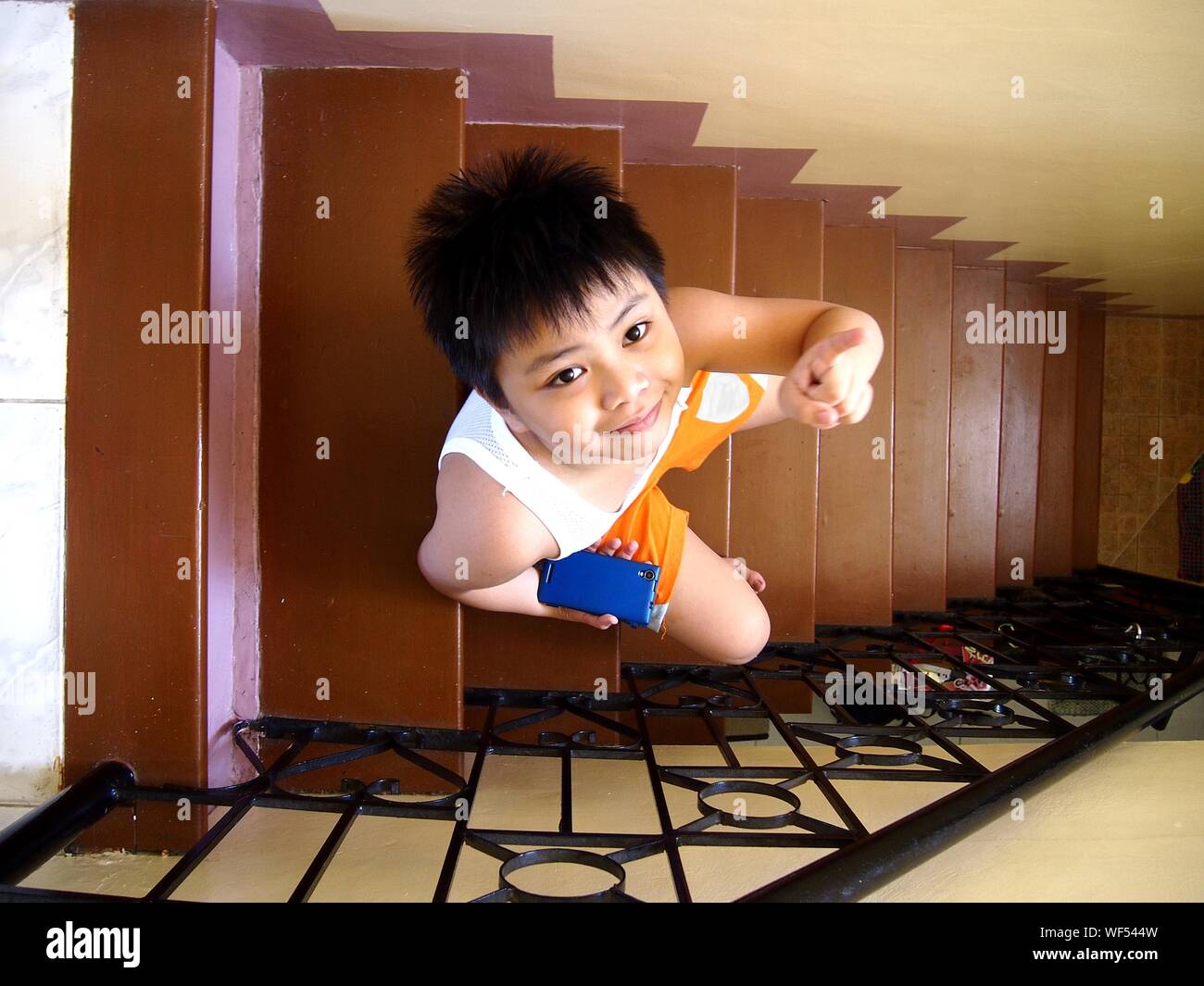 Portrait Of Cute Boy Pointing On Steps At Home Stock Photo - Alamy