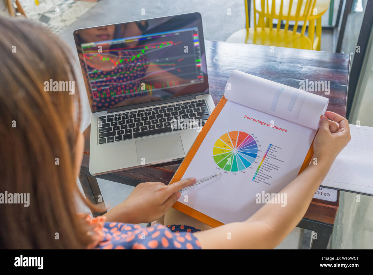 Female financial executive working on pie chart document and laptop ...