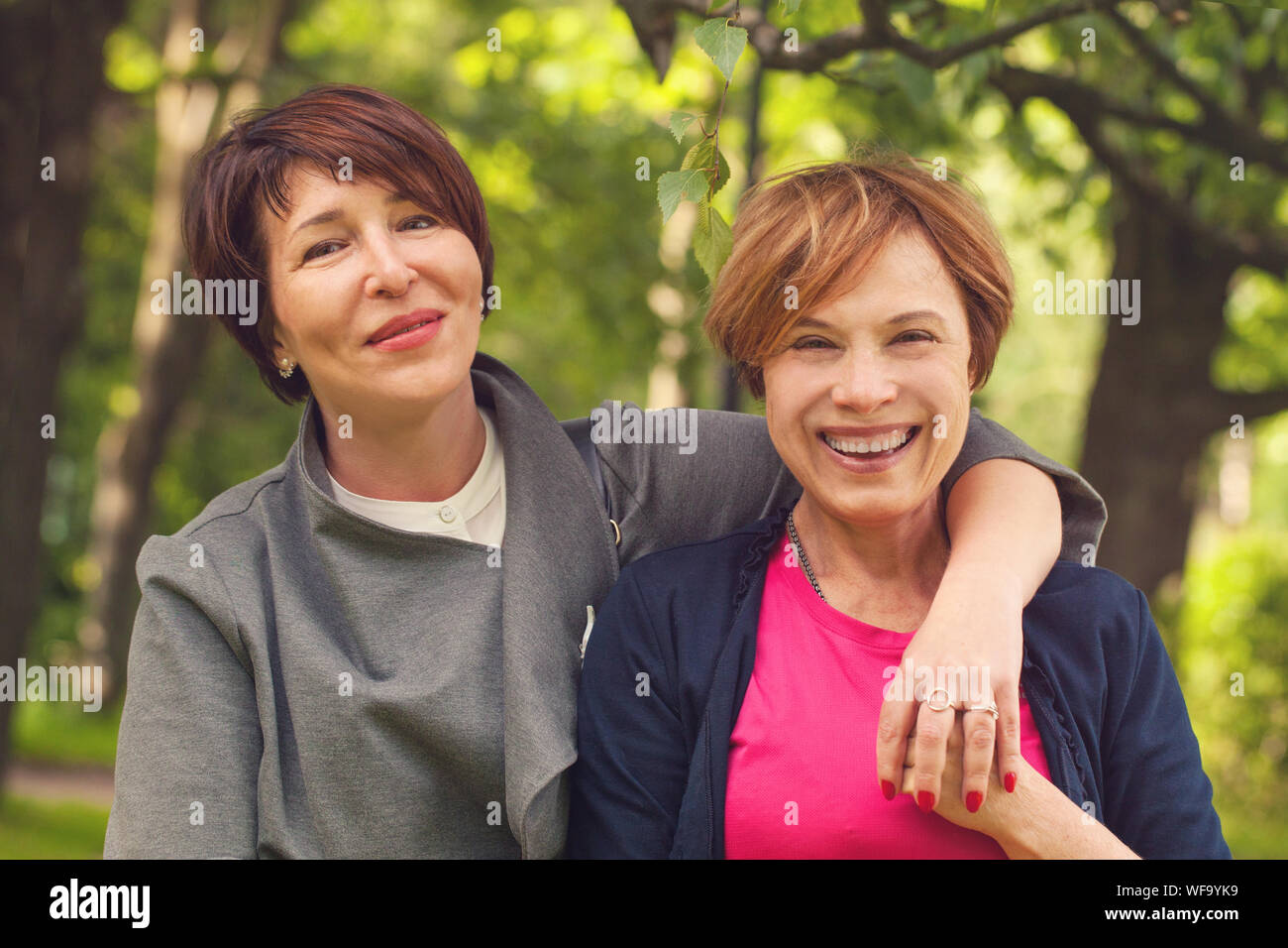 Two happy women walking in summer park, portrait Stock Photo - Alamy