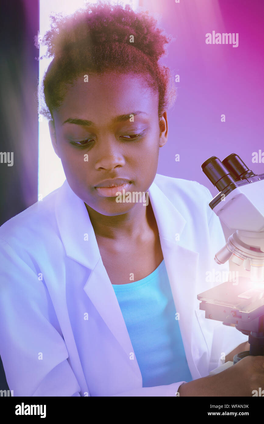 African scientist or graduate student in lab coat working with modern ...