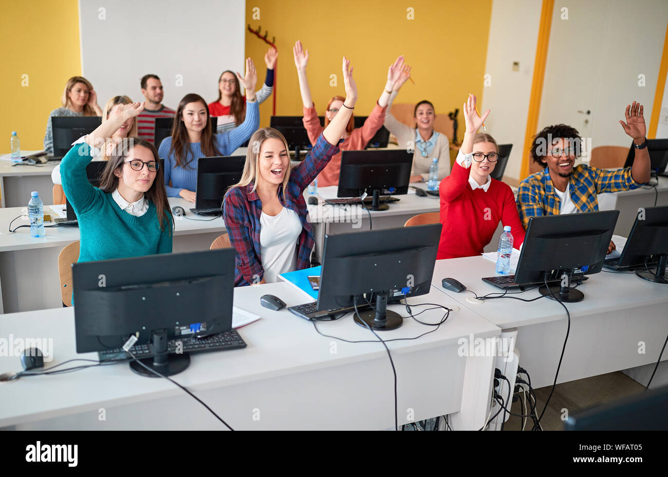 Happy students raising hand in class on university campus Stock Photo ...