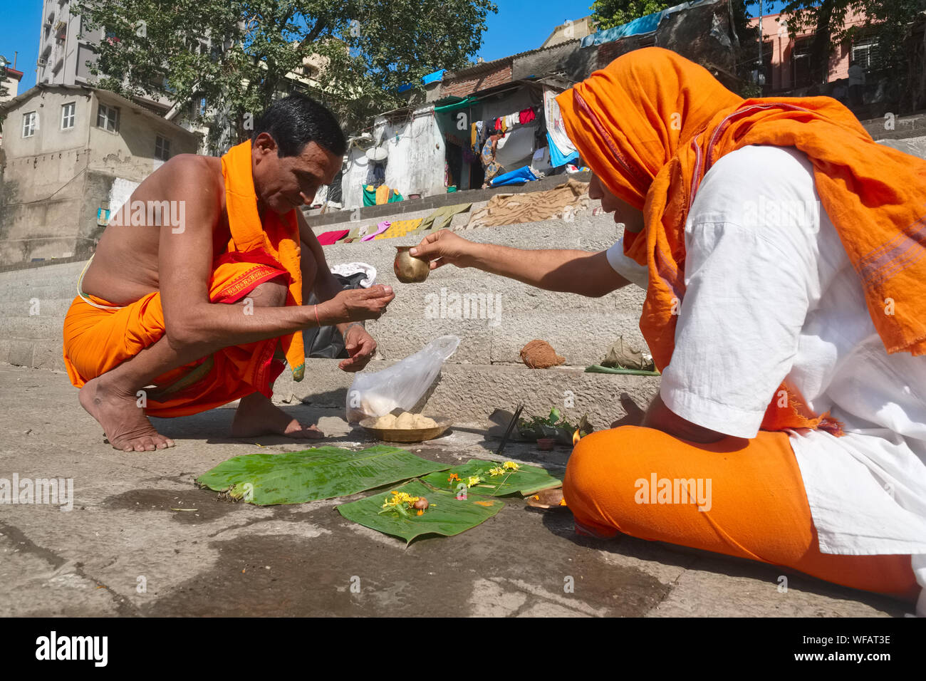 A Hindu priest (l) conducting memorial rites with the relative (r) of a ...