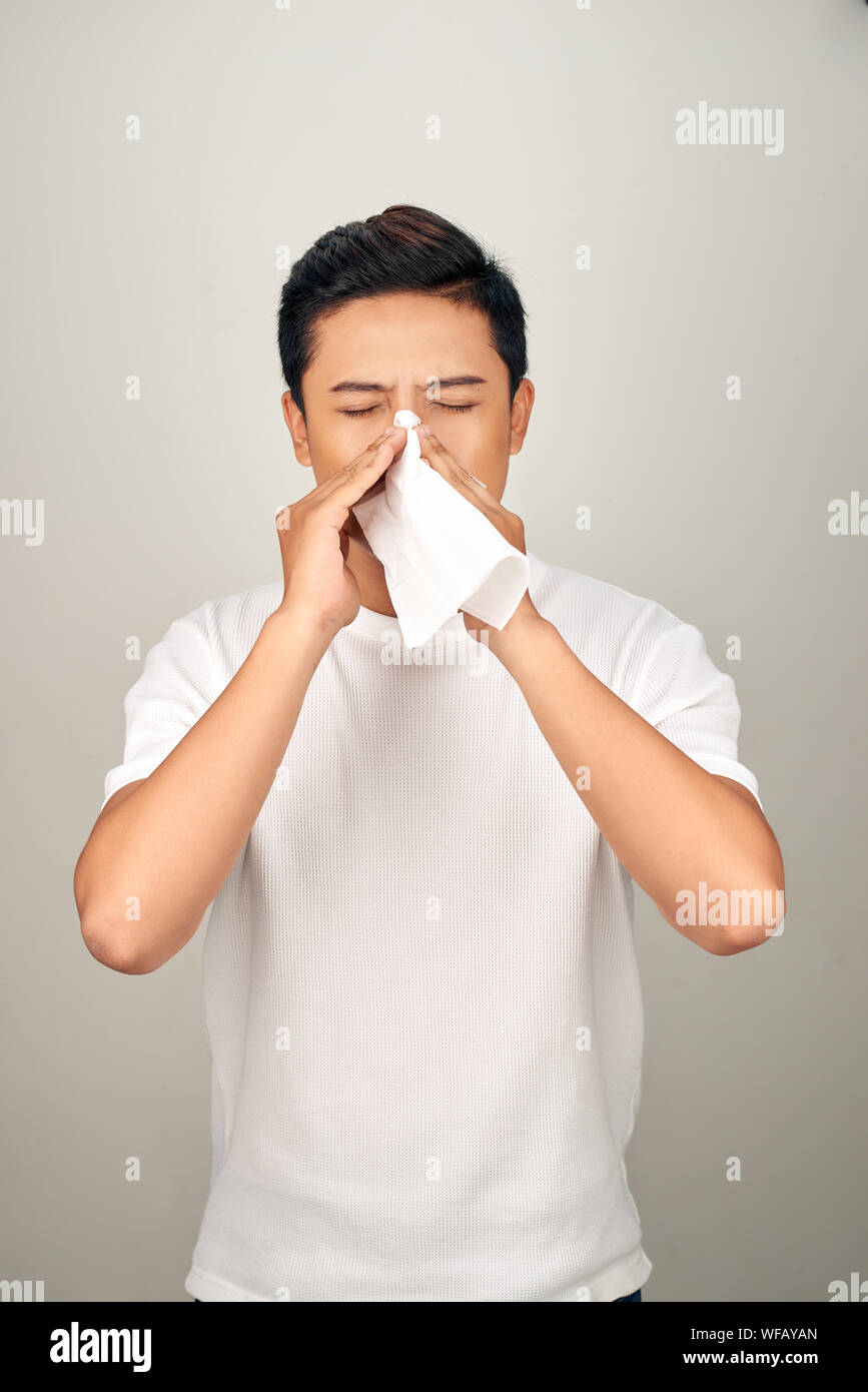 Closeup of sick Asian man blowing nose into tissue, suffering from ...