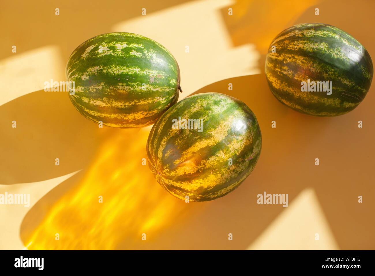 Overhead view of three watermelons on a table in sunlight Stock Photo ...