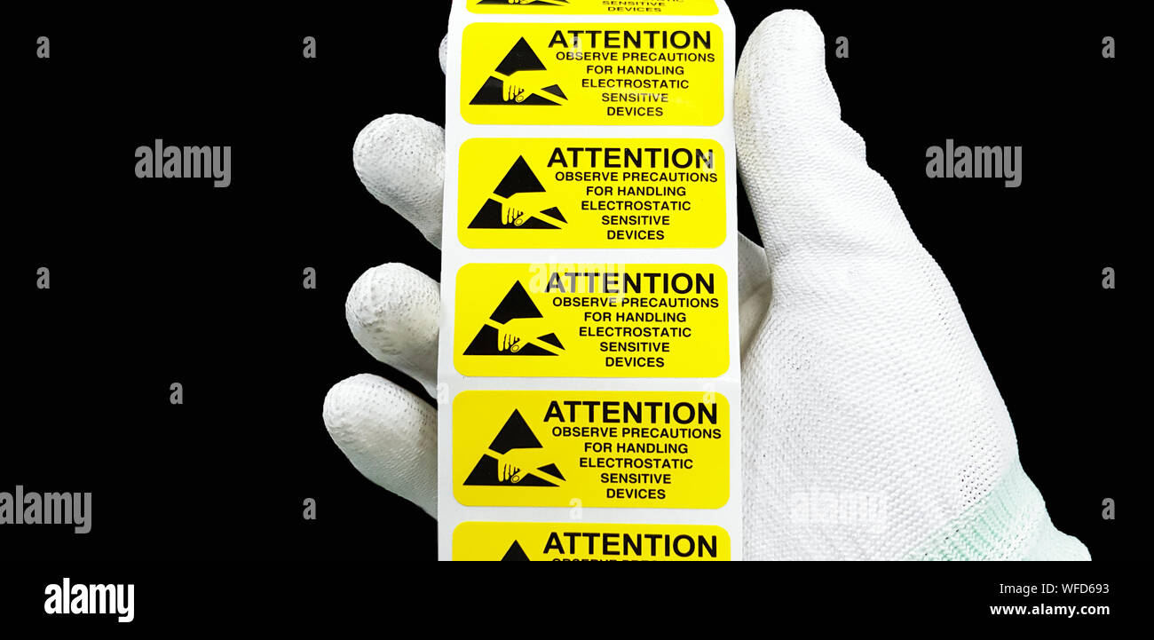 Hand holding ESD symbol label with antistatic gloves on black ...