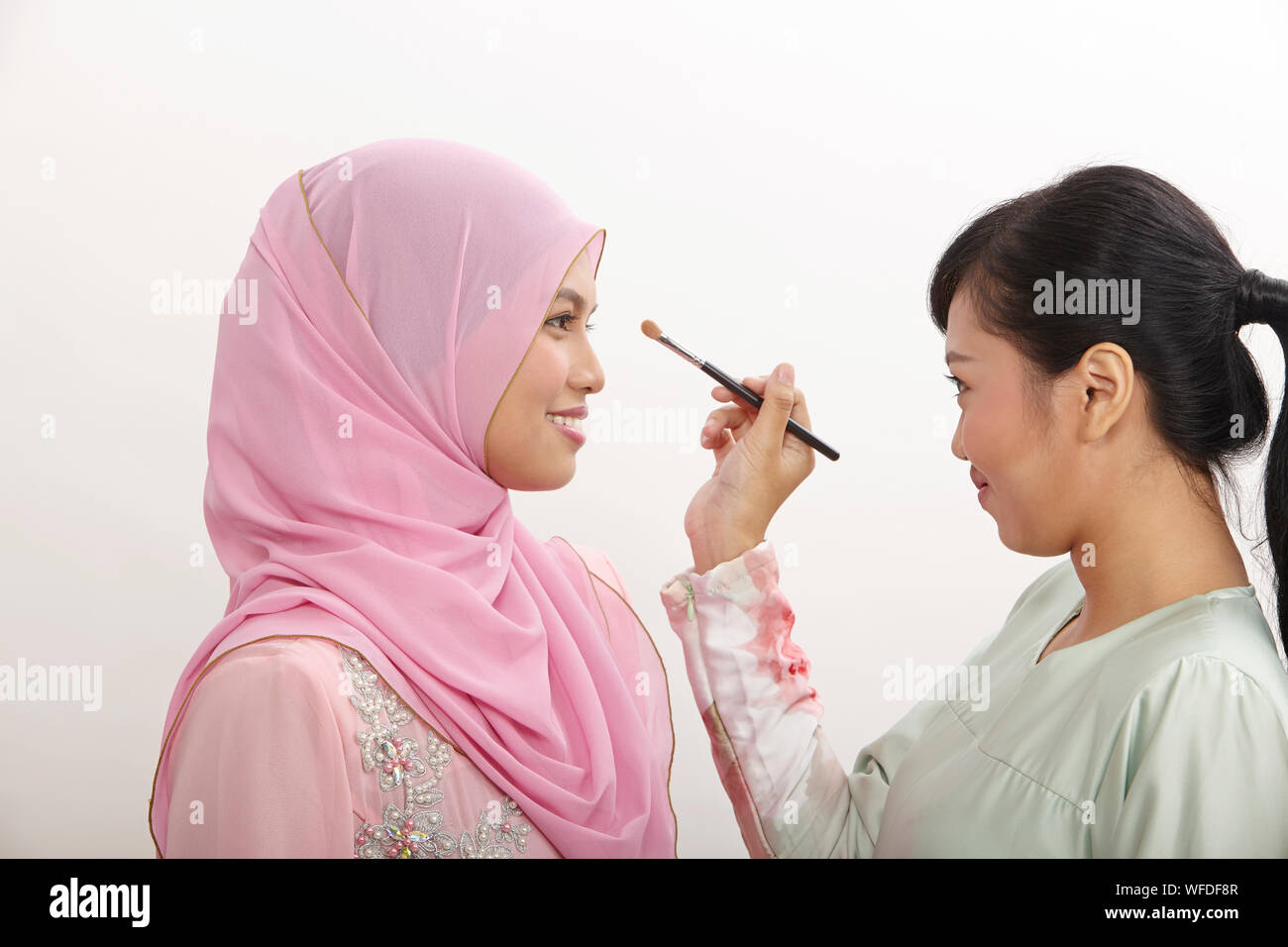 friendship, woman helping her friend putting makeup on the white ...