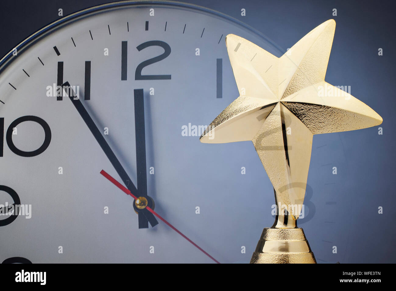 Gold star on an award trophy in front of a clock showing five to twelve ...