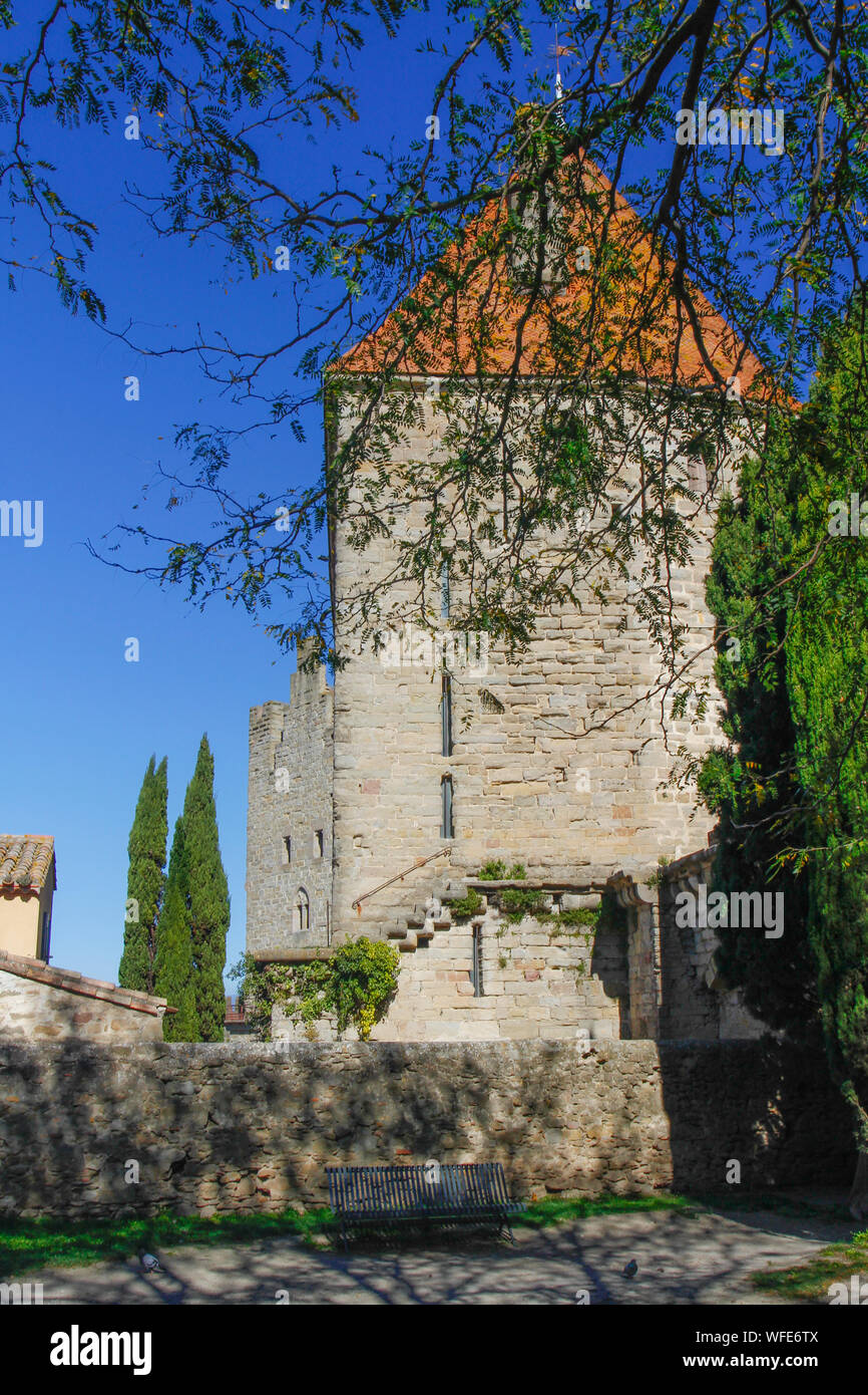 Bench seat underneath shade of tree with stone watchtower and blue sky ...