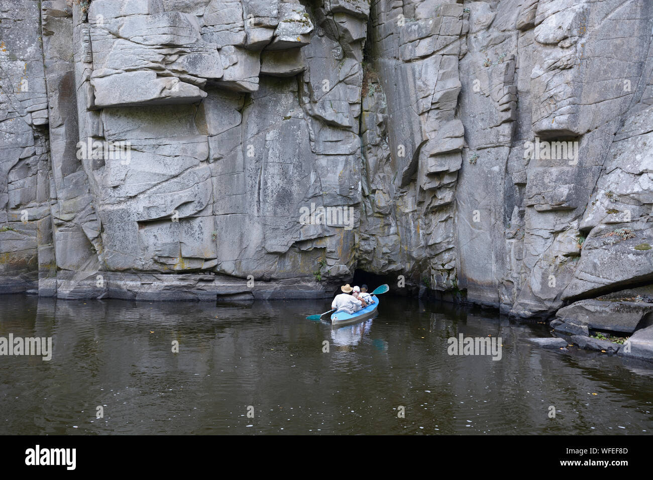 Canoe with people aboard going inside of a cave of rocks. Buksky canyon ...