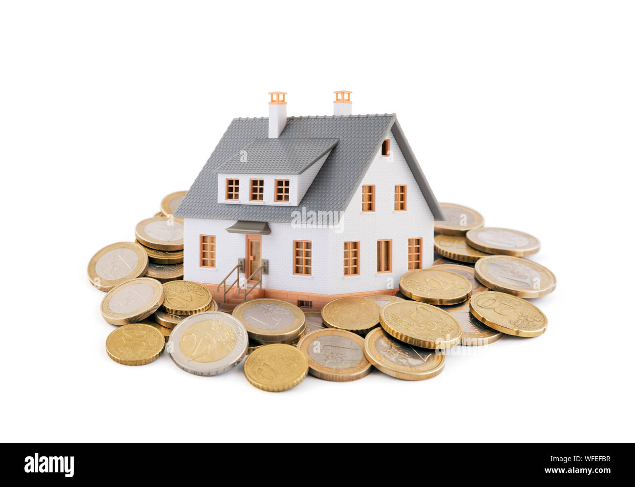 Small toy house with euro coins on white background Stock Photo - Alamy