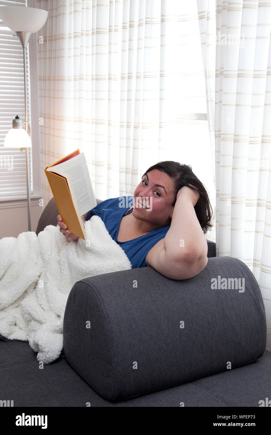 Woman curled up with a book hi-res stock photography and images - Alamy