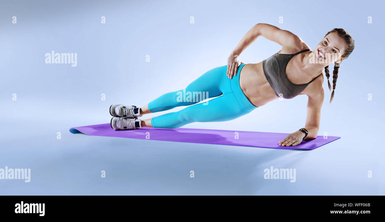 Sport. Muscular woman on a plank position use fitness gum. Muscular and ...