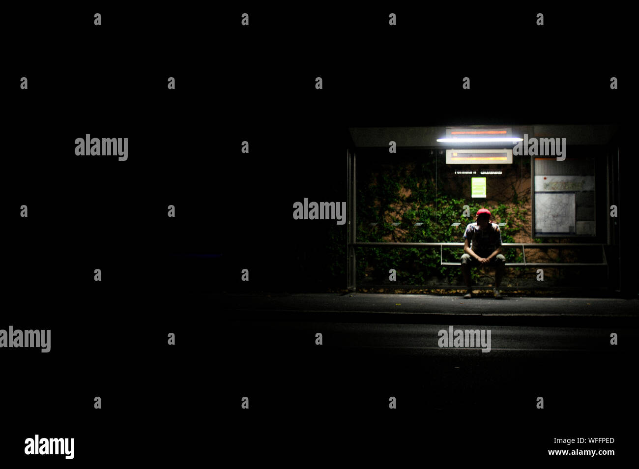 Man Waiting At Bus Stop During Night Stock Photo - Alamy