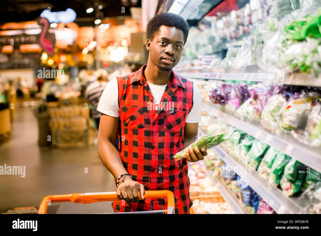 African man shopping in vegetable section at supermarket. Black man ...