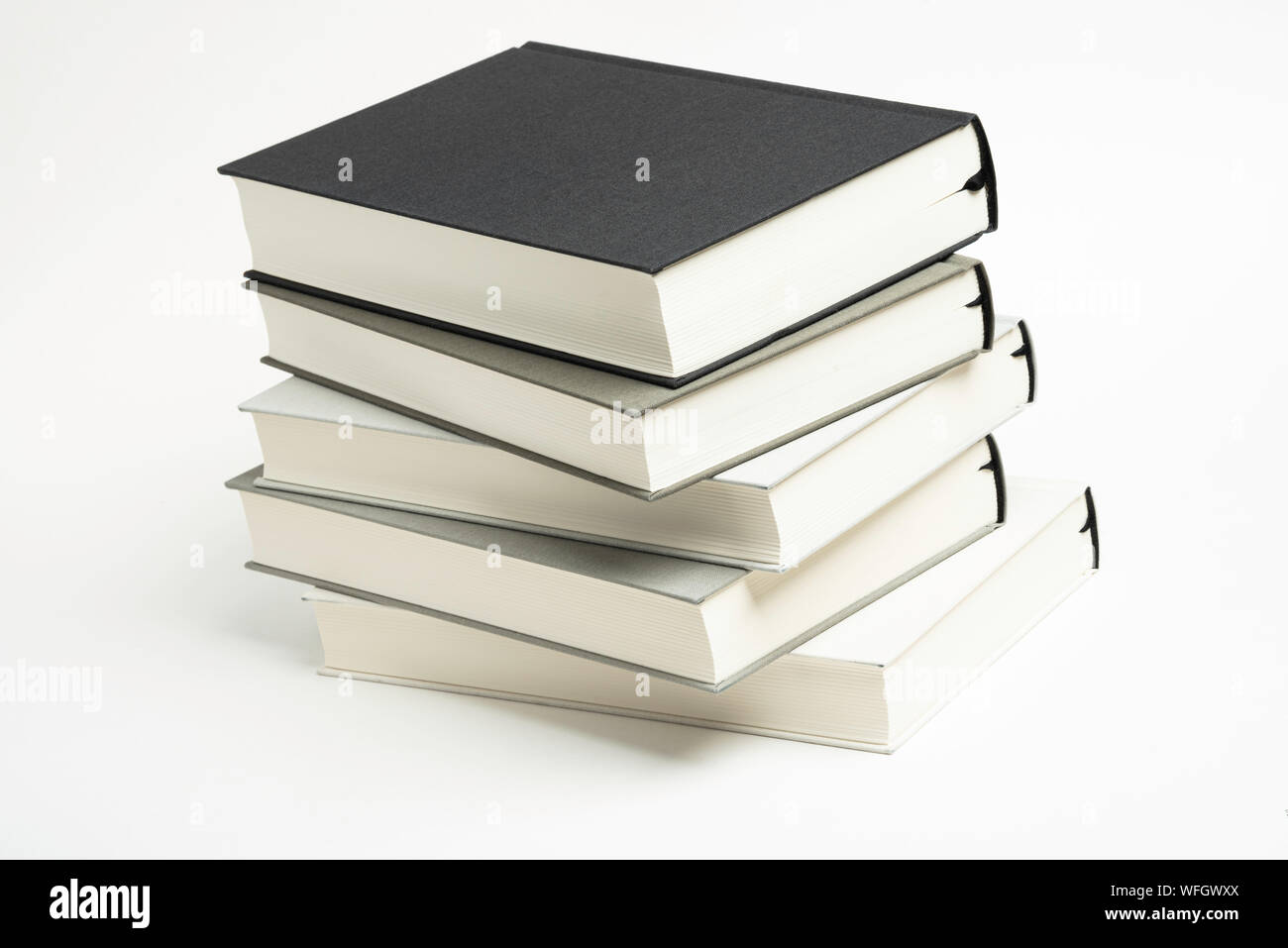 A disarrayed stack of five monochromatic cloth-bound books set on a ...