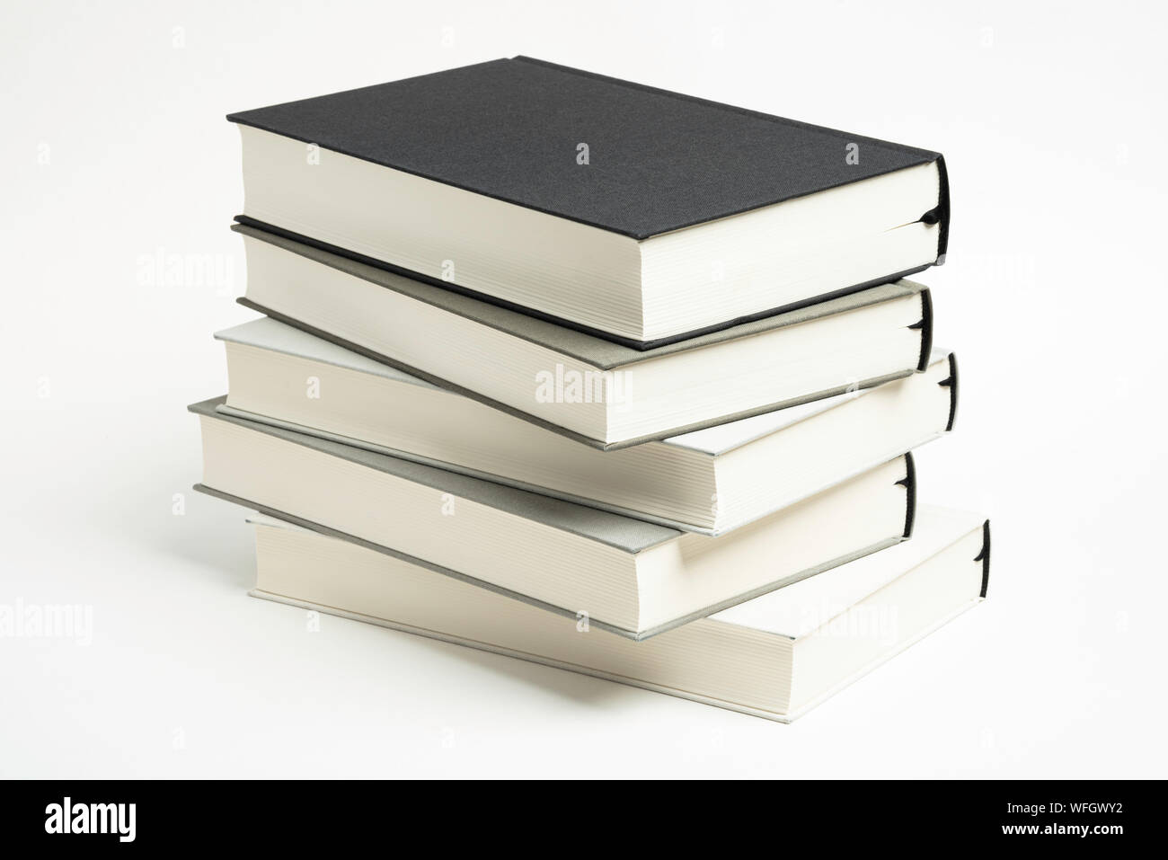 A disarrayed stack of five monochromatic cloth-bound books set on a ...