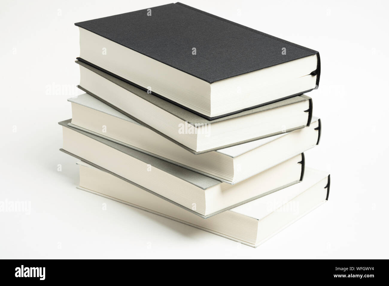 A disarrayed stack of five monochromatic cloth-bound books set on a ...