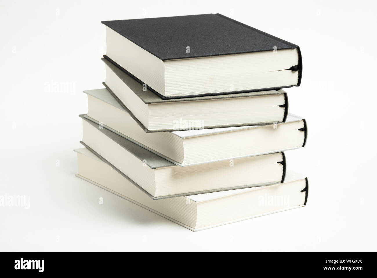 A disarrayed stack of five monochromatic cloth-bound books set on a ...