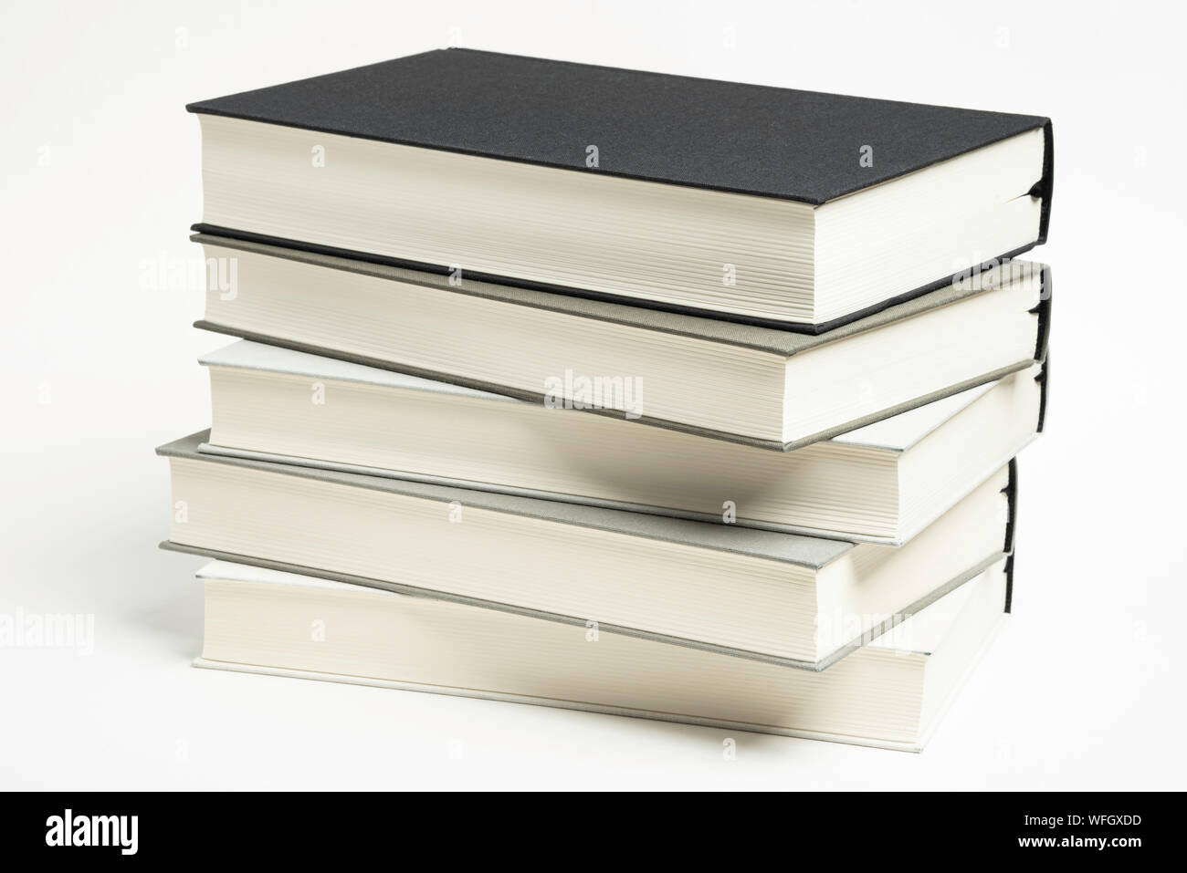 A disarrayed stack of five monochromatic cloth-bound books set on a ...