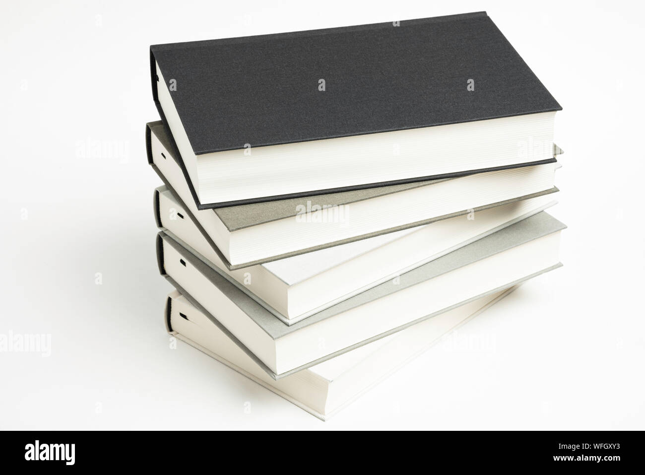 A disarrayed stack of five monochromatic cloth-bound books set on a ...