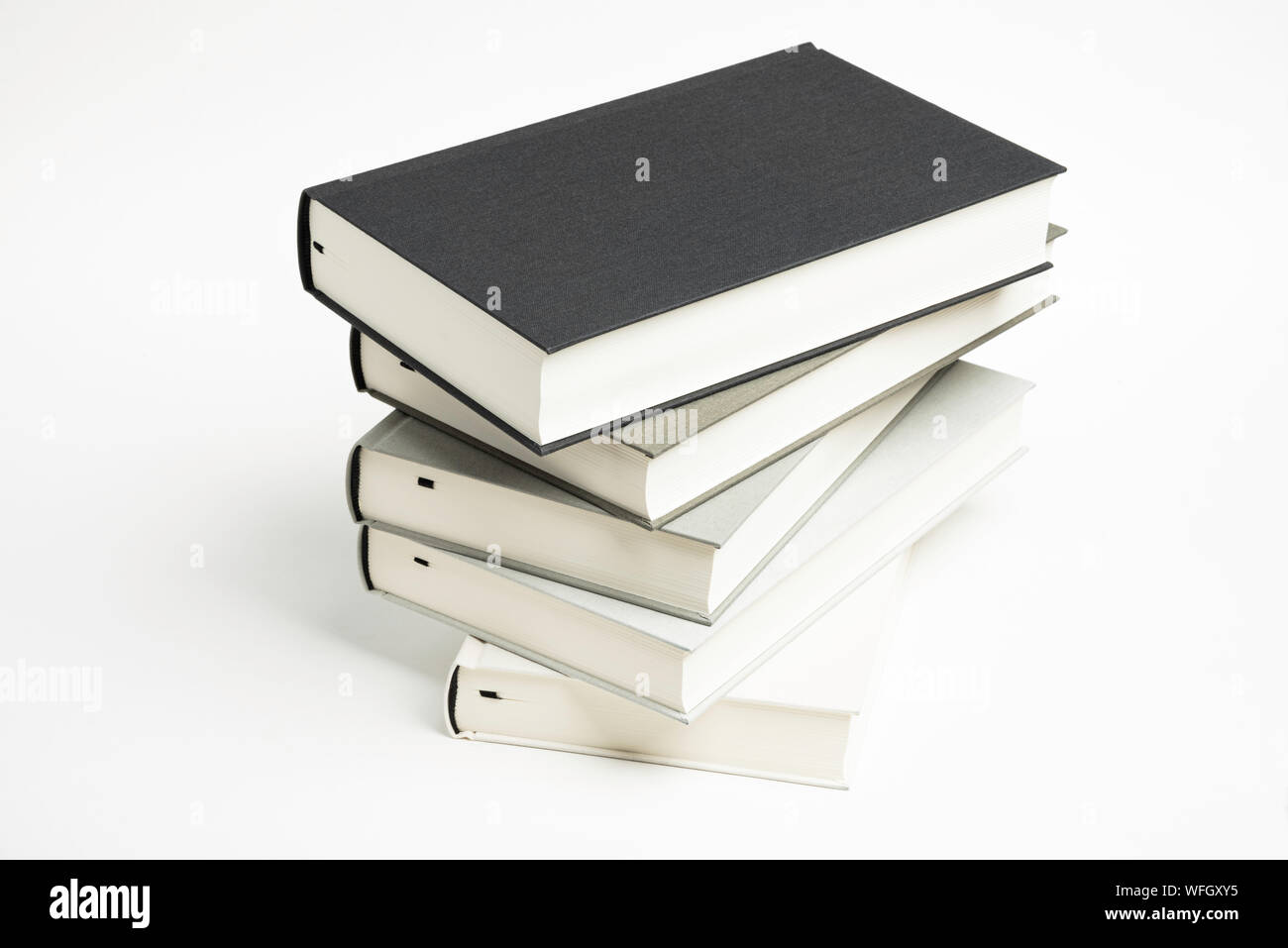 A disarrayed stack of five monochromatic cloth-bound books set on a ...