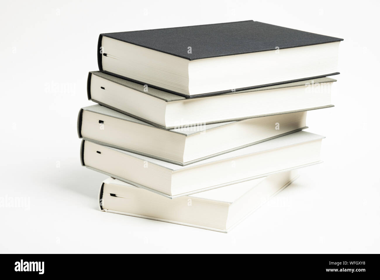 A disarrayed stack of five monochromatic cloth-bound books set on a ...